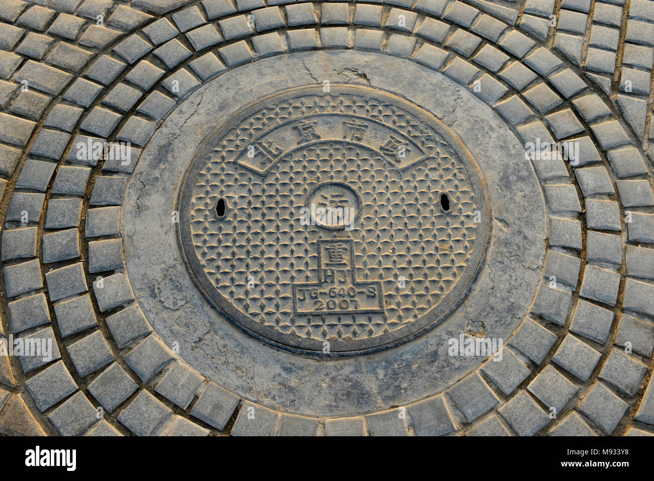 Manhole cover (sewerage) on a pedestrianised street in central Beijing ...