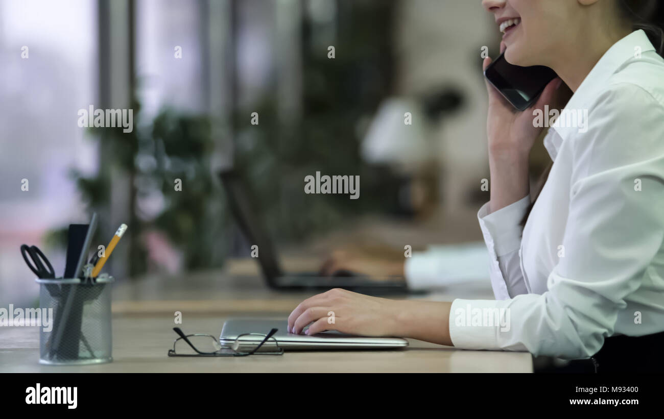 Happy young lady receiving phone call at office, talking with smile on ...