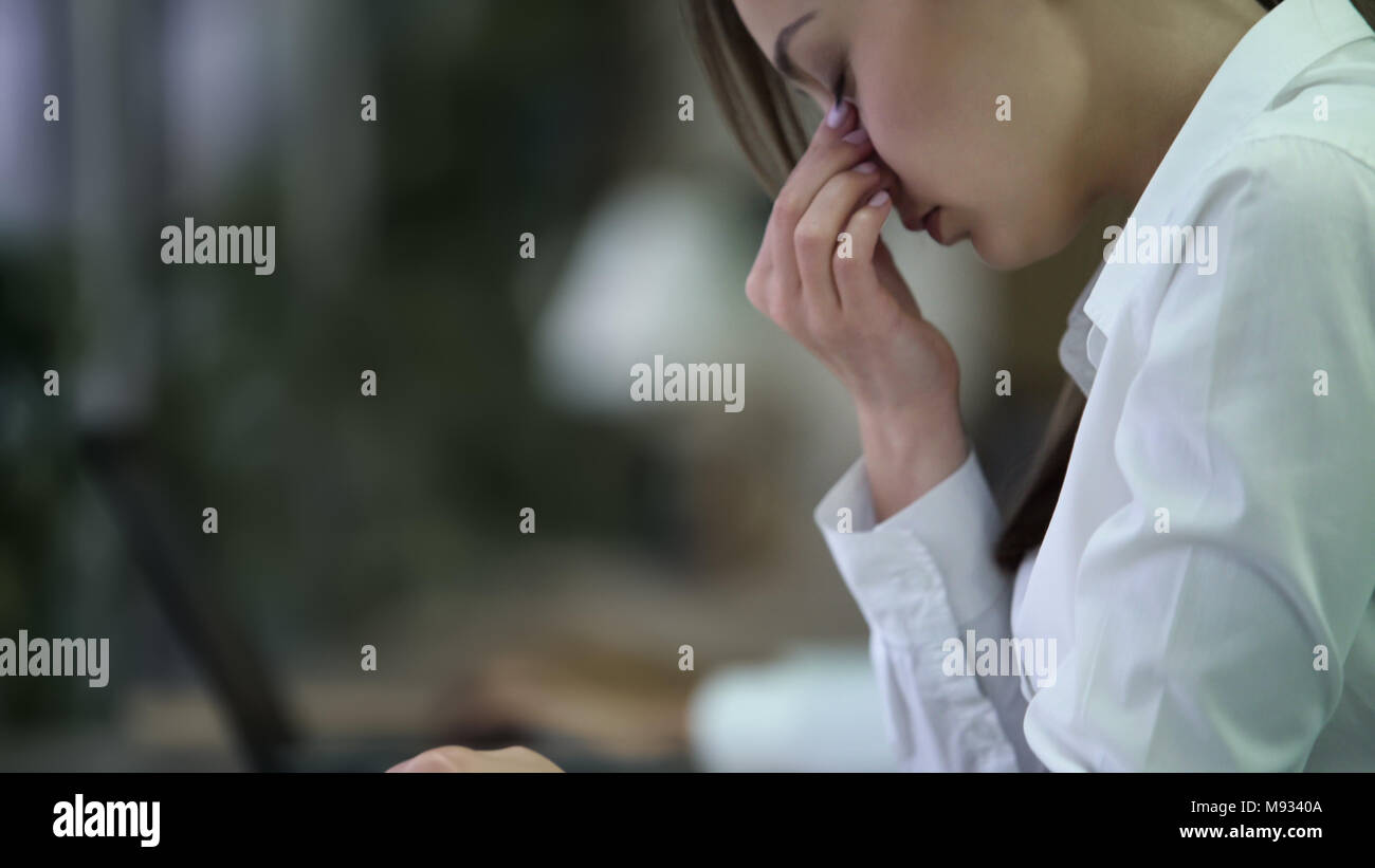 Overworked young business woman rubbing eyes, tired after difficult day ...