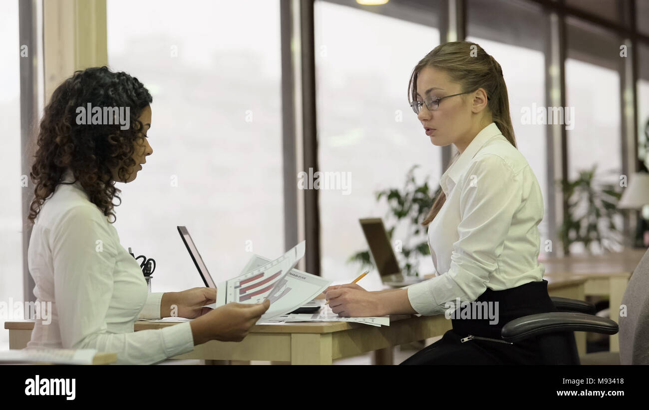 Strict female team leader checking papers with employee, brainstorming ...