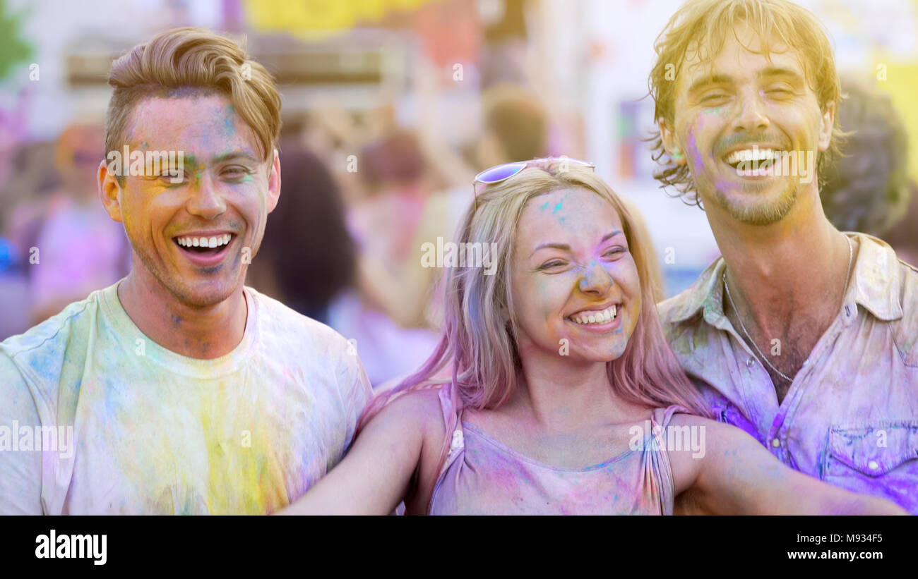 Excited faces of beautiful young people covered in colors laughing at ...