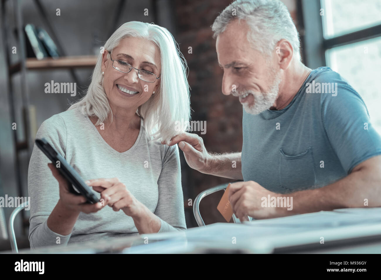 Bespectacled aged woman smiling and showing the tablet Stock Photo - Alamy
