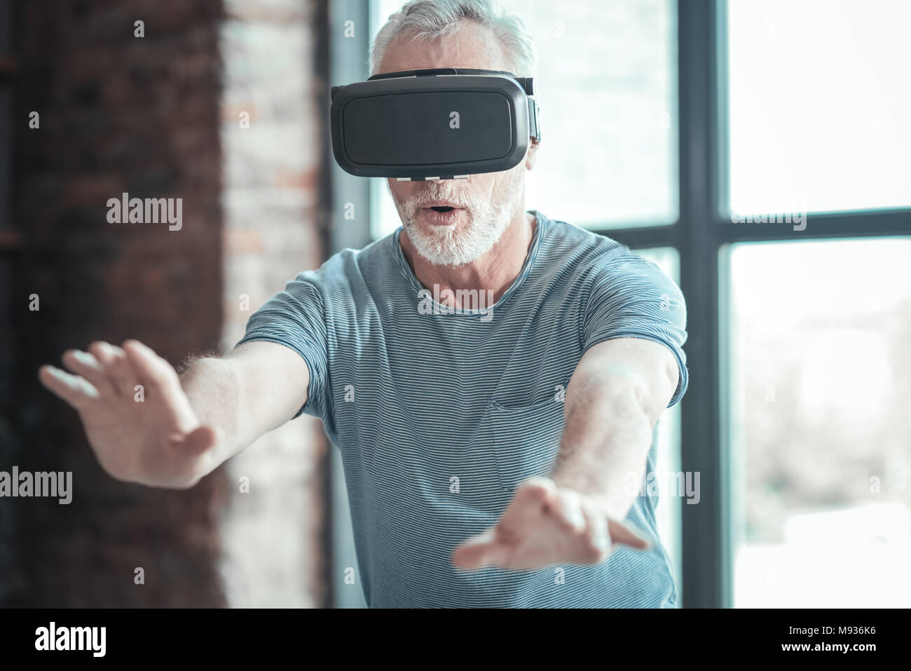 Amazed senior man using the gadget and holding hands up Stock Photo - Alamy