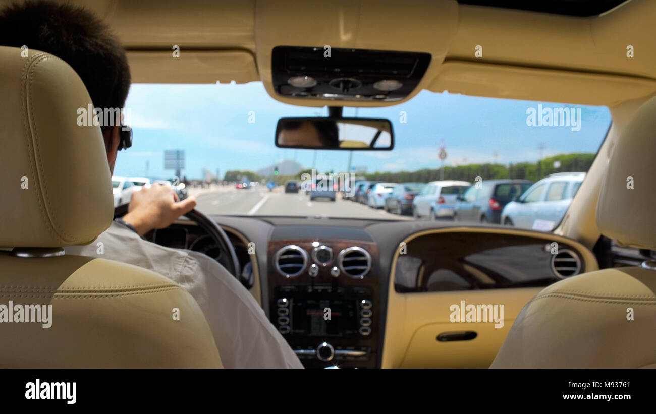 Busy rich male driving car in resort city, businessman going to meeting ...