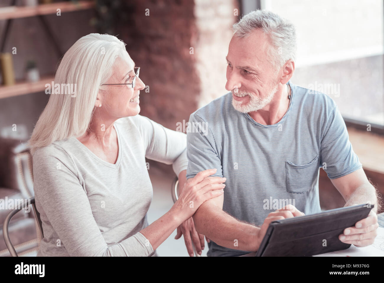 Cute bespectacled woman looking at her husband touching to him Stock ...