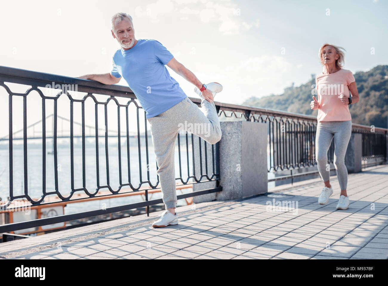 Satisfied unshaken man holding by the railing doing stretching ...