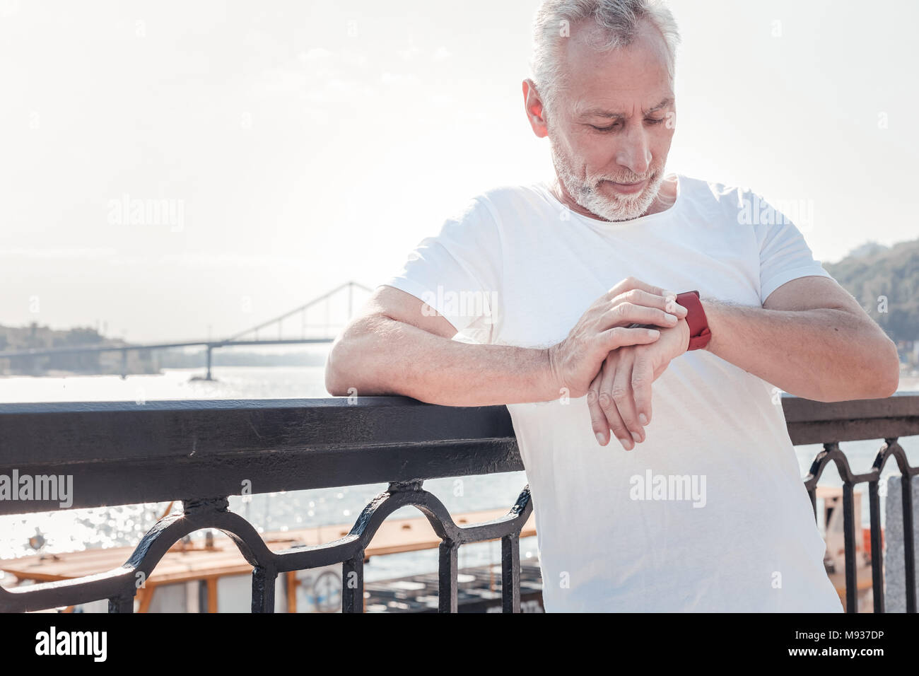 Smart aged man standing and looking at his watch Stock Photo - Alamy