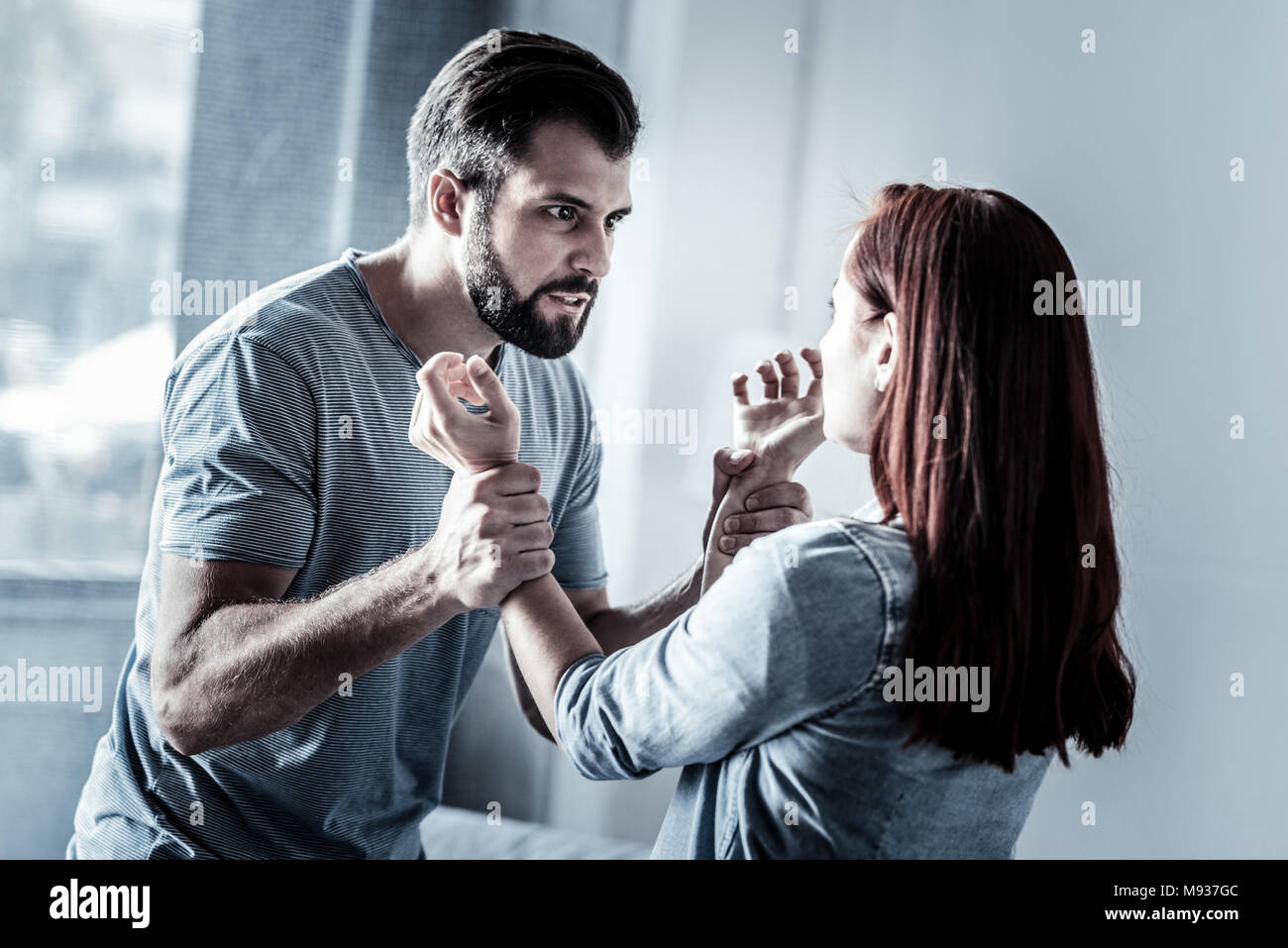 Angry evil man standing and holding wmans hands Stock Photo - Alamy