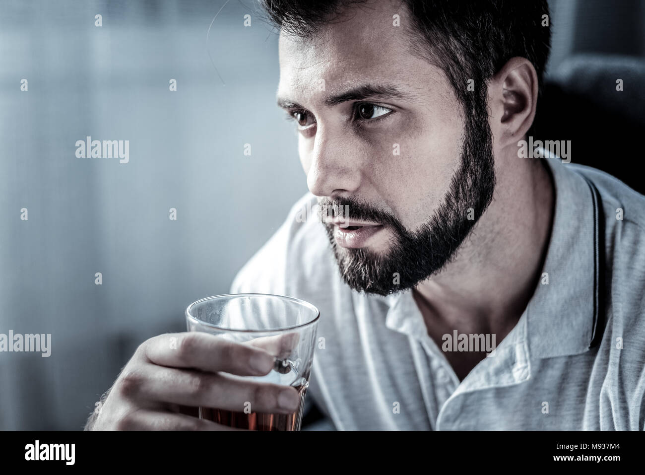 Thoughtful concentrated man looking aside and drinking Stock Photo - Alamy