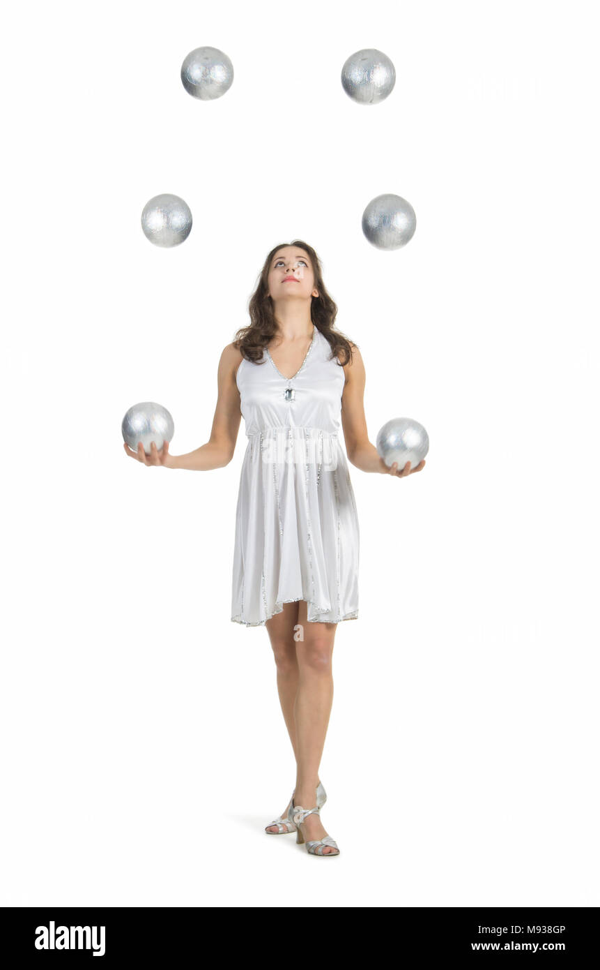 A young female circus performer, juggles silver balls. Studio shot on ...