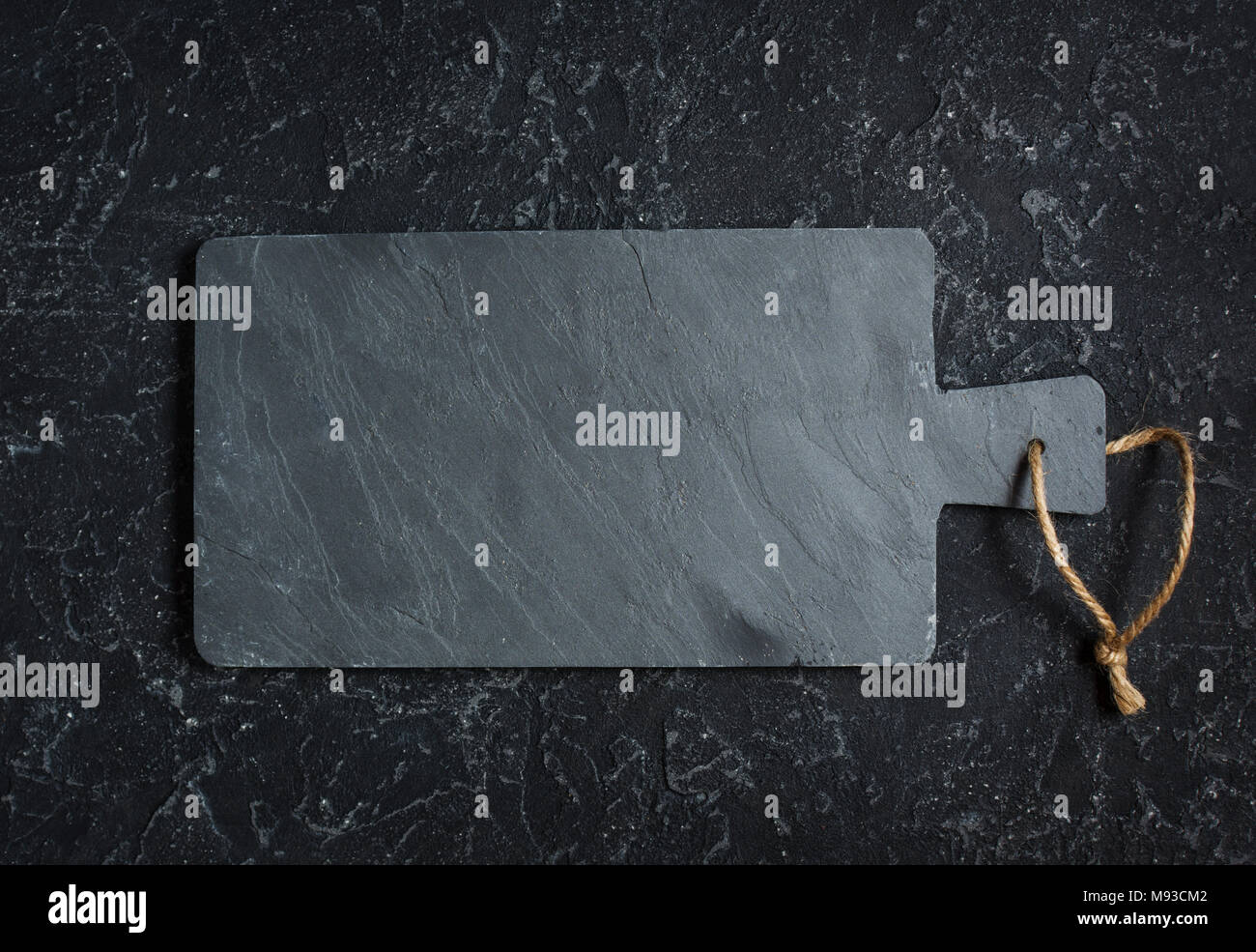 Black old-fashioned stone and slate cutting board on black background ...