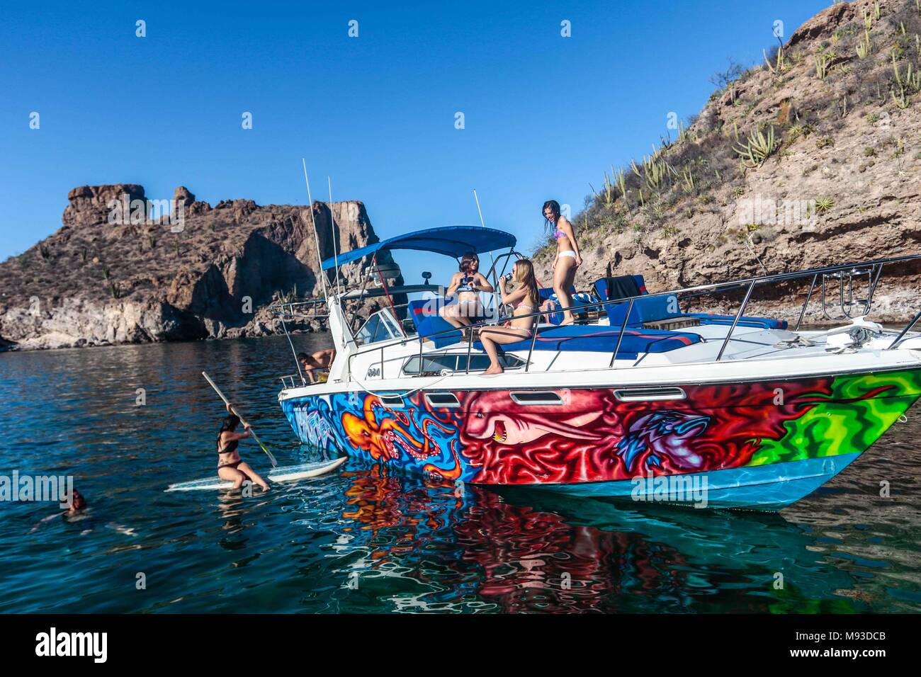 Teenage vacationers enjoy a sunny day, ride a yacht through the bay and ...