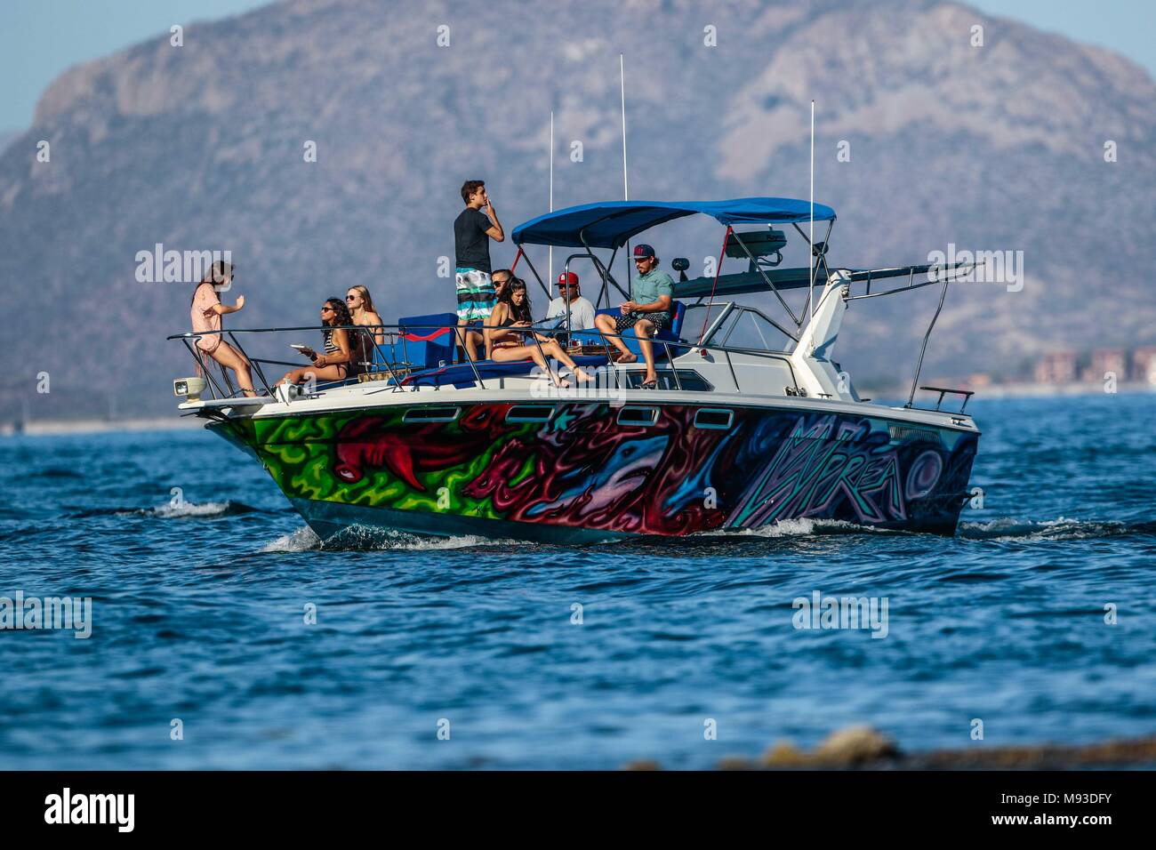 Teenage vacationers enjoy a sunny day, ride a yacht through the bay and ...