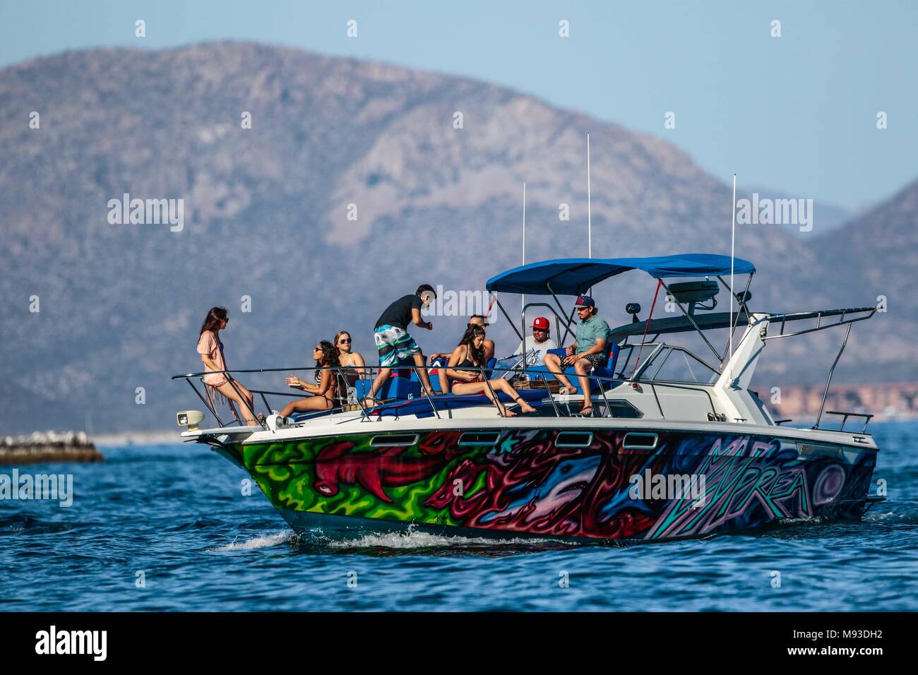 Teenage vacationers enjoy a sunny day, ride a yacht through the bay and ...