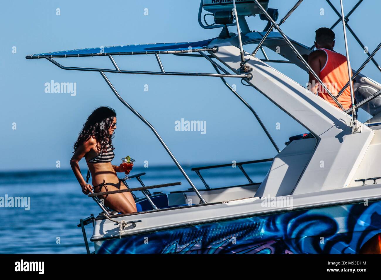Teenage vacationers enjoy a sunny day, ride a yacht through the bay and ...