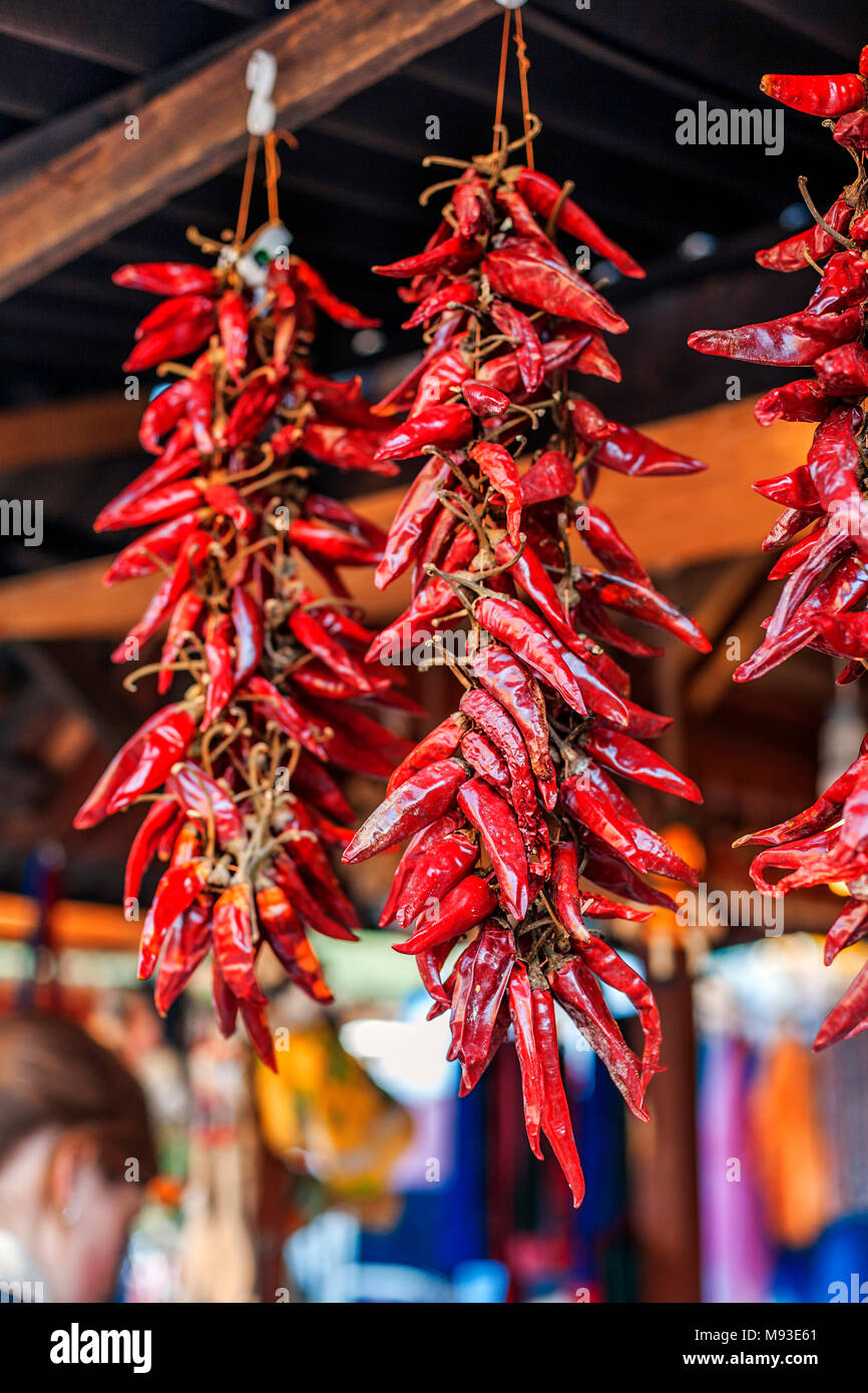 Glossy red dried chillies hanging in bunches at a Castle Hill Market ...