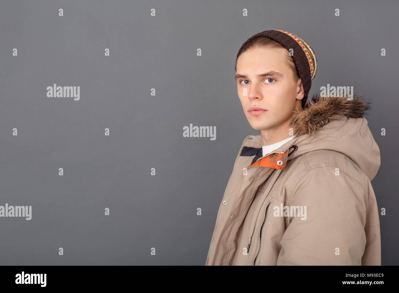 Young guy wearing winter clothes studio isolated on grey wall looking ...