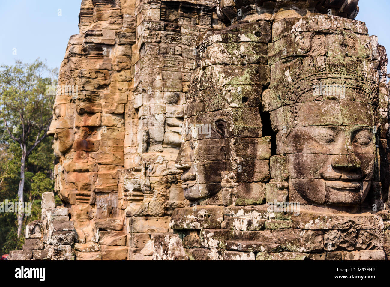 Multiple large faces of the Buddha are carved in to the side of the ...