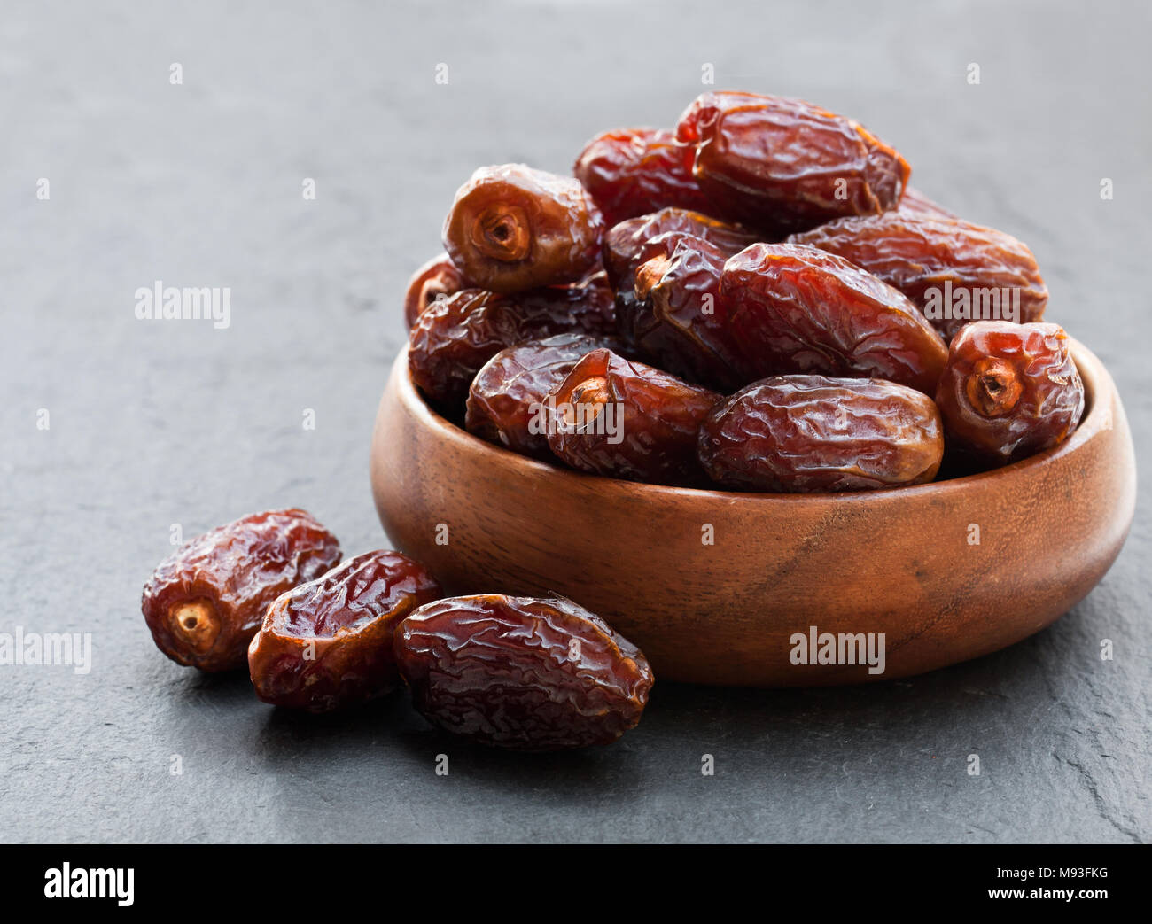 Dried dates in wooden bowl on black stone background Stock Photo - Alamy