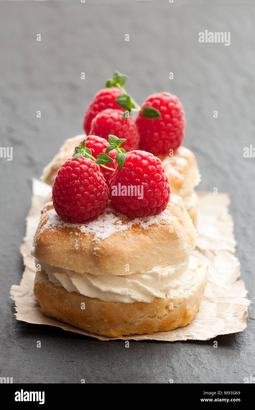 Traditional scones with raspberry and cream on black stone background ...