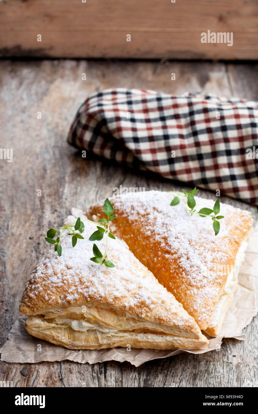 Freshly baked turnovers with white cream on wooden table Stock Photo ...