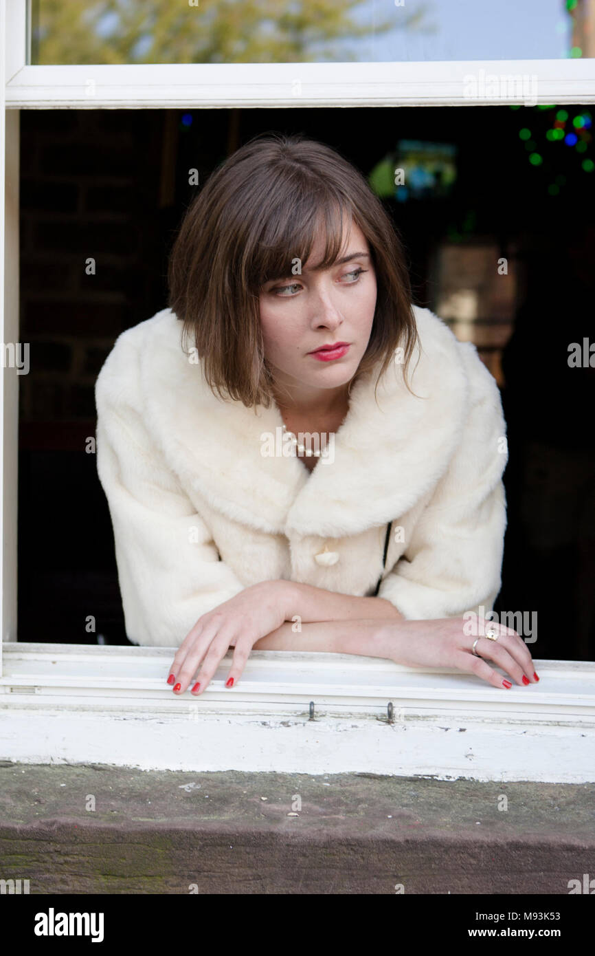 A woman with red lipstick, wearing a white fur jacket and a pearl ...