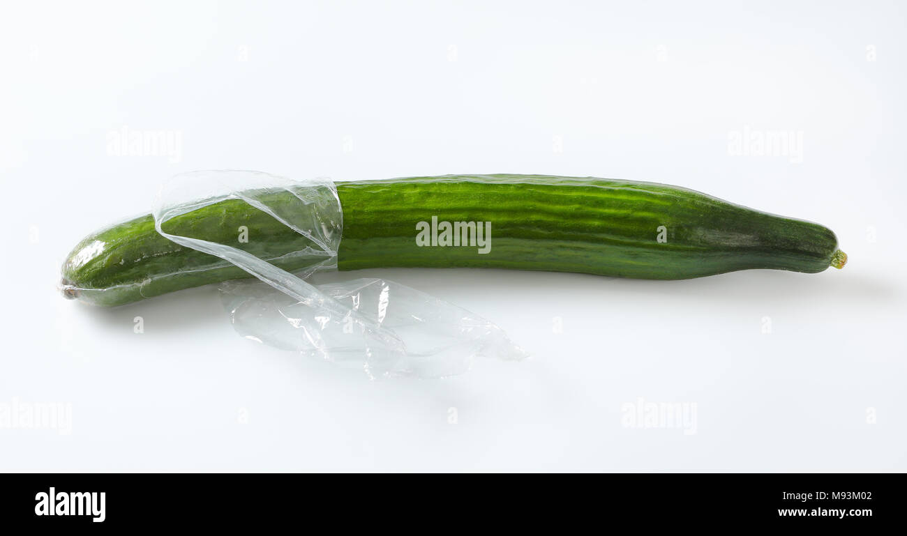 single long cucumber unwrapped and unpeeled on white background Stock ...