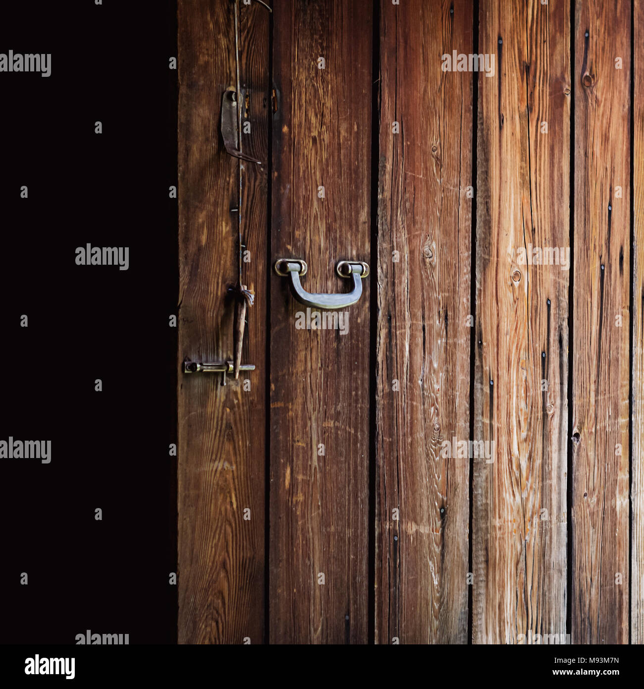 Opened old weathered wooden door with polished metal handle, steel ...