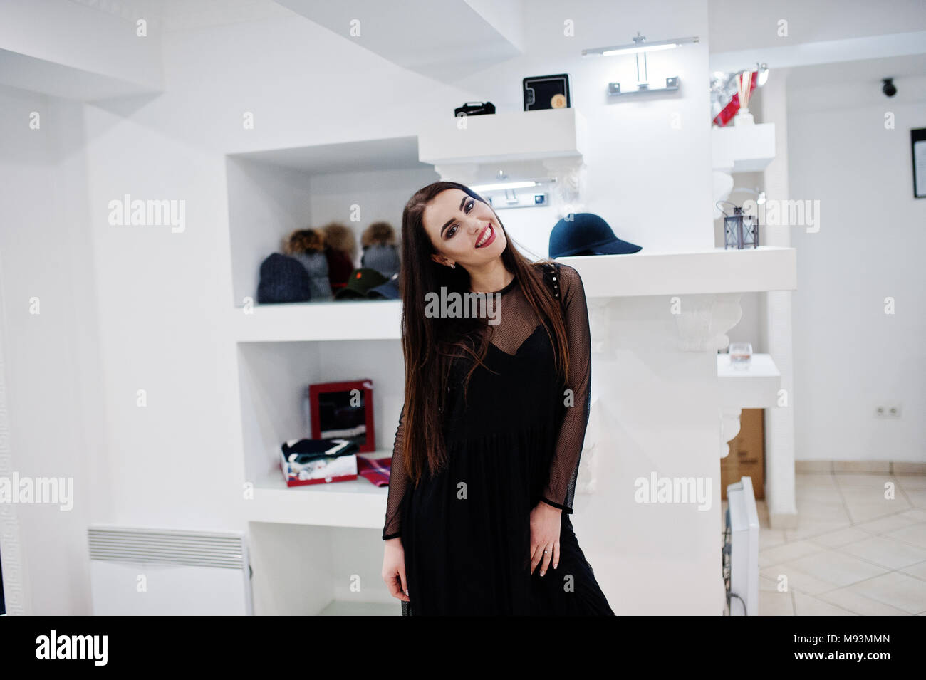 Brunette gorgeous girl in the clothing store boutique at black dress ...