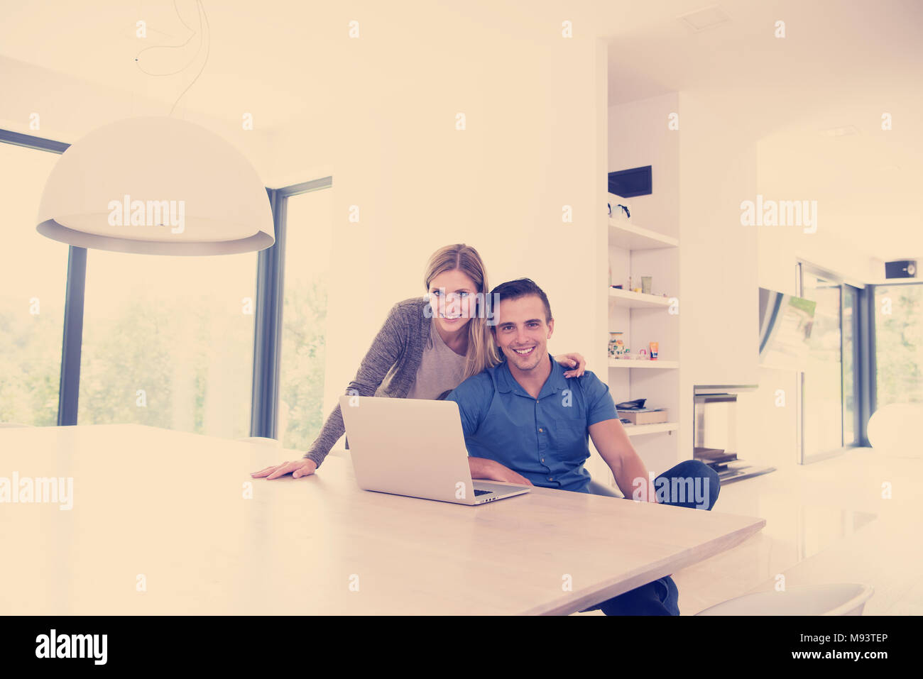Young couple using laptop computer at luxury home together, looking at ...
