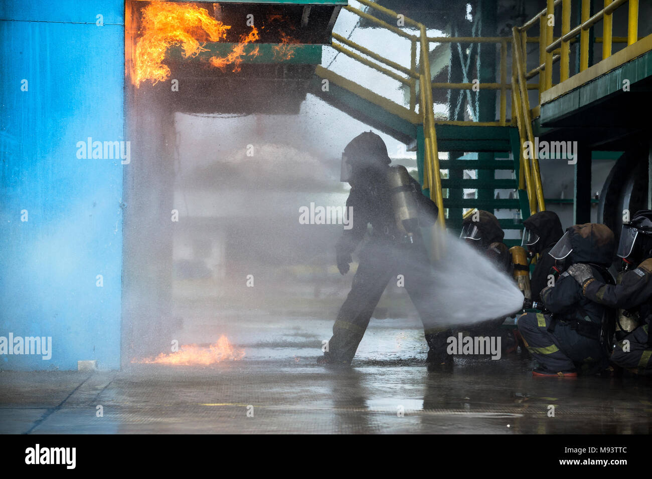 Firemen using water from hose for fire fighting at firefight training ...