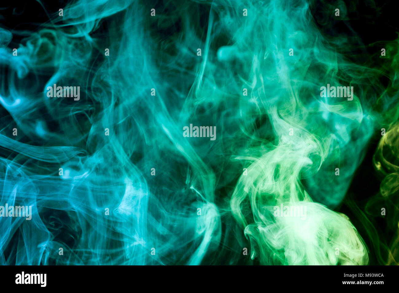 Thick colorful smoke of blue and green on a black isolated background ...