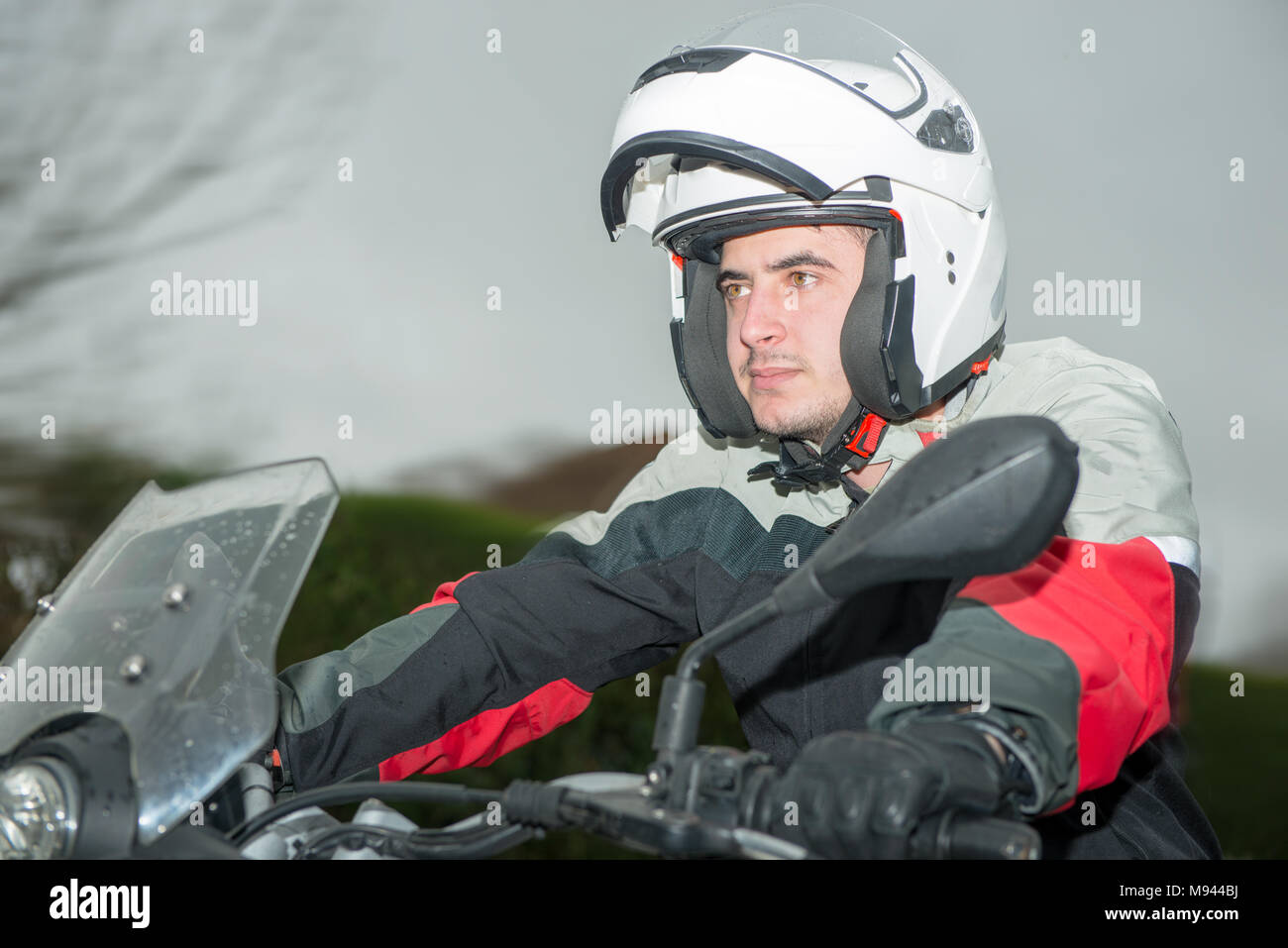 a young man sitting on motorcycle and has helmet on his head Stock ...
