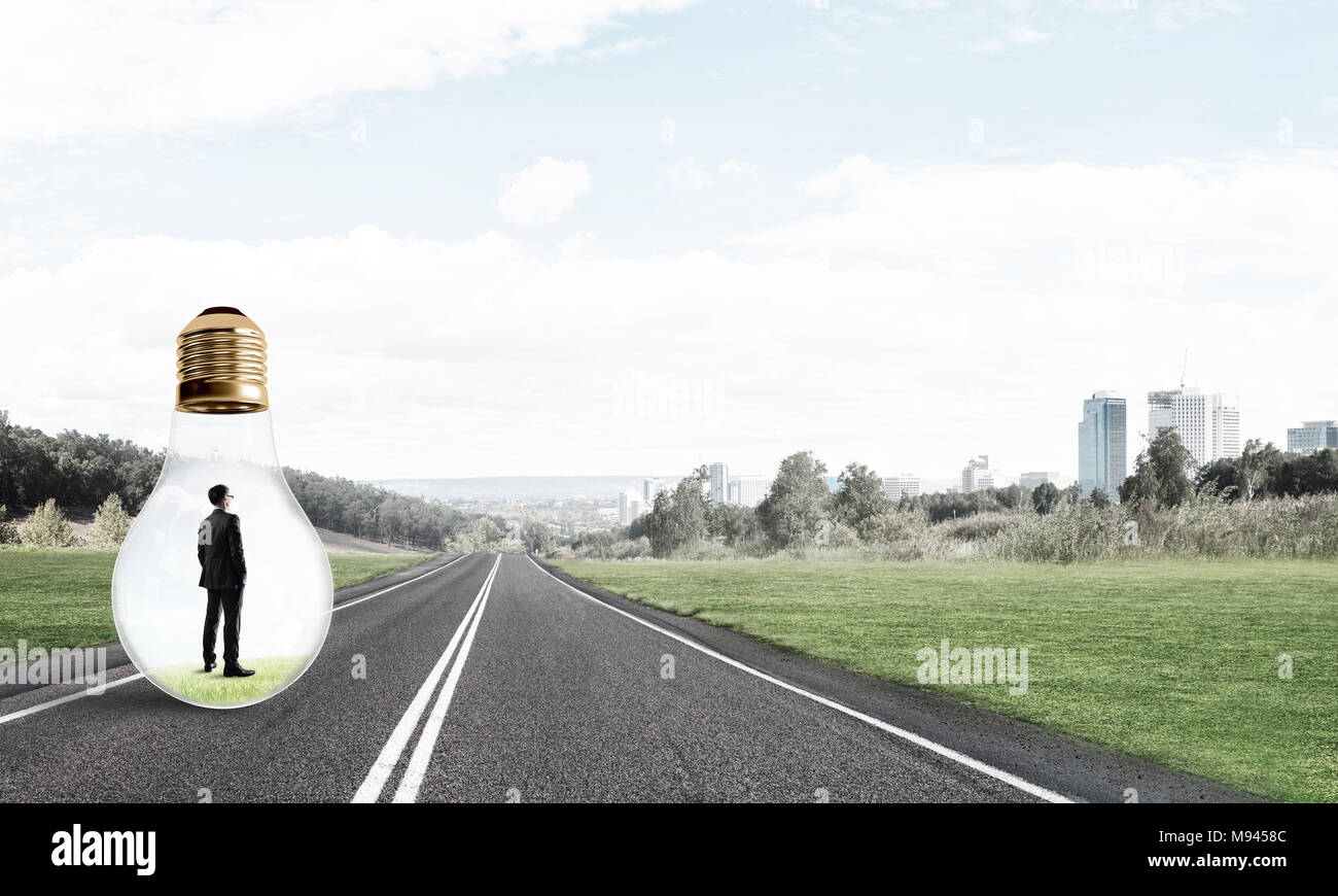 Young businessman trapped inside of light bulb on asphalt road Stock ...