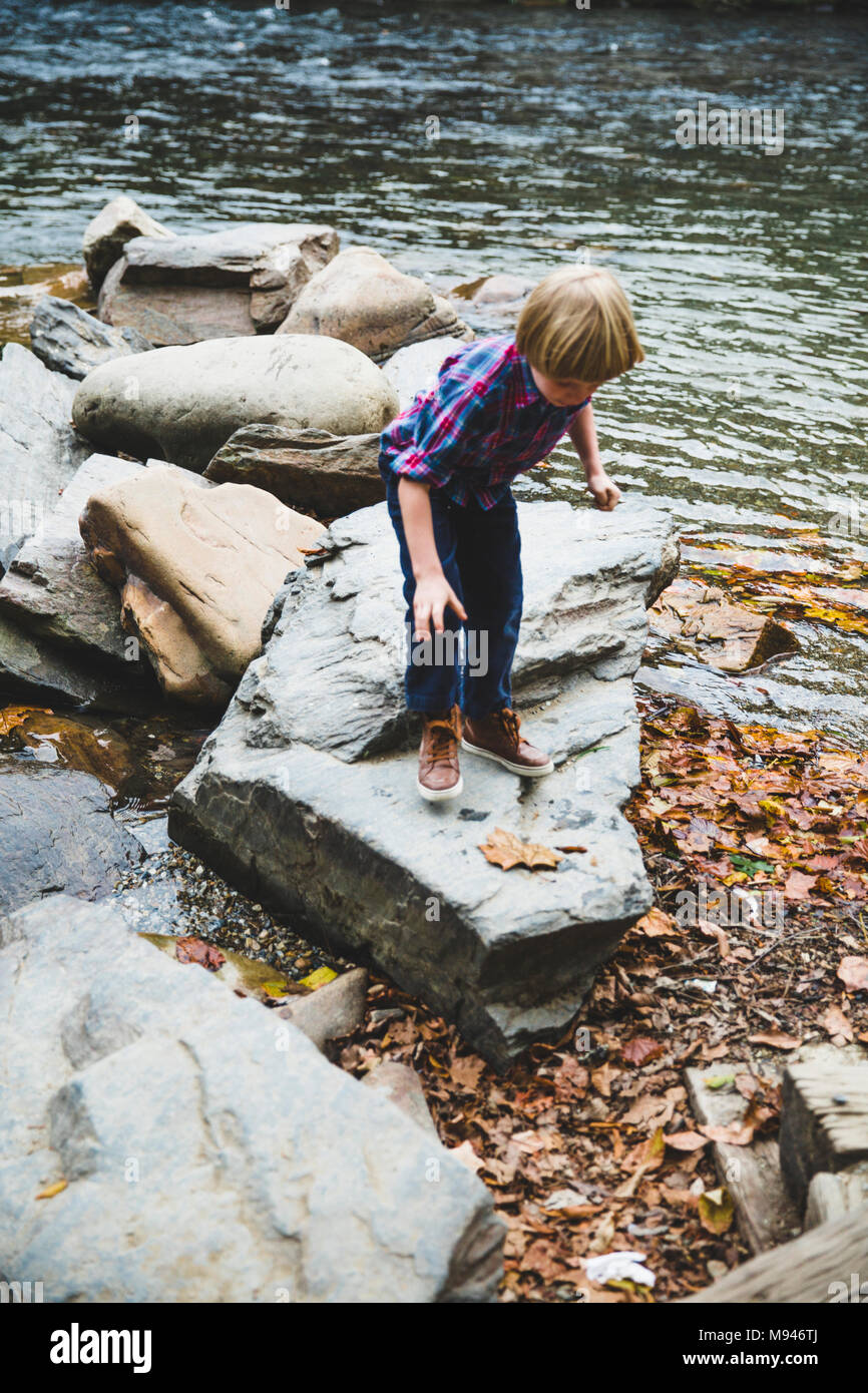 Boy playing on rocks next to river Stock Photo - Alamy