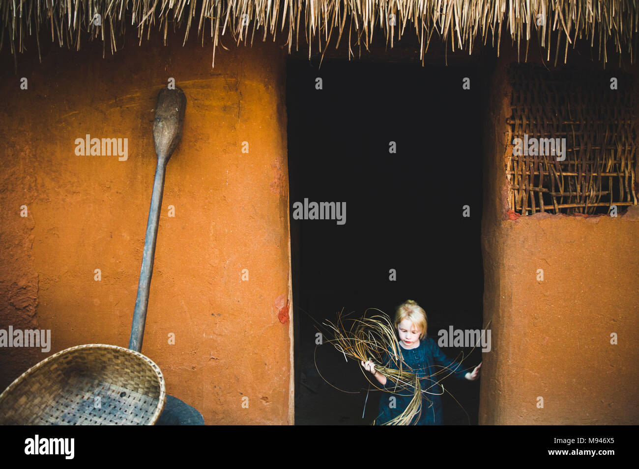 Girl carrying straw out of hut Stock Photo - Alamy