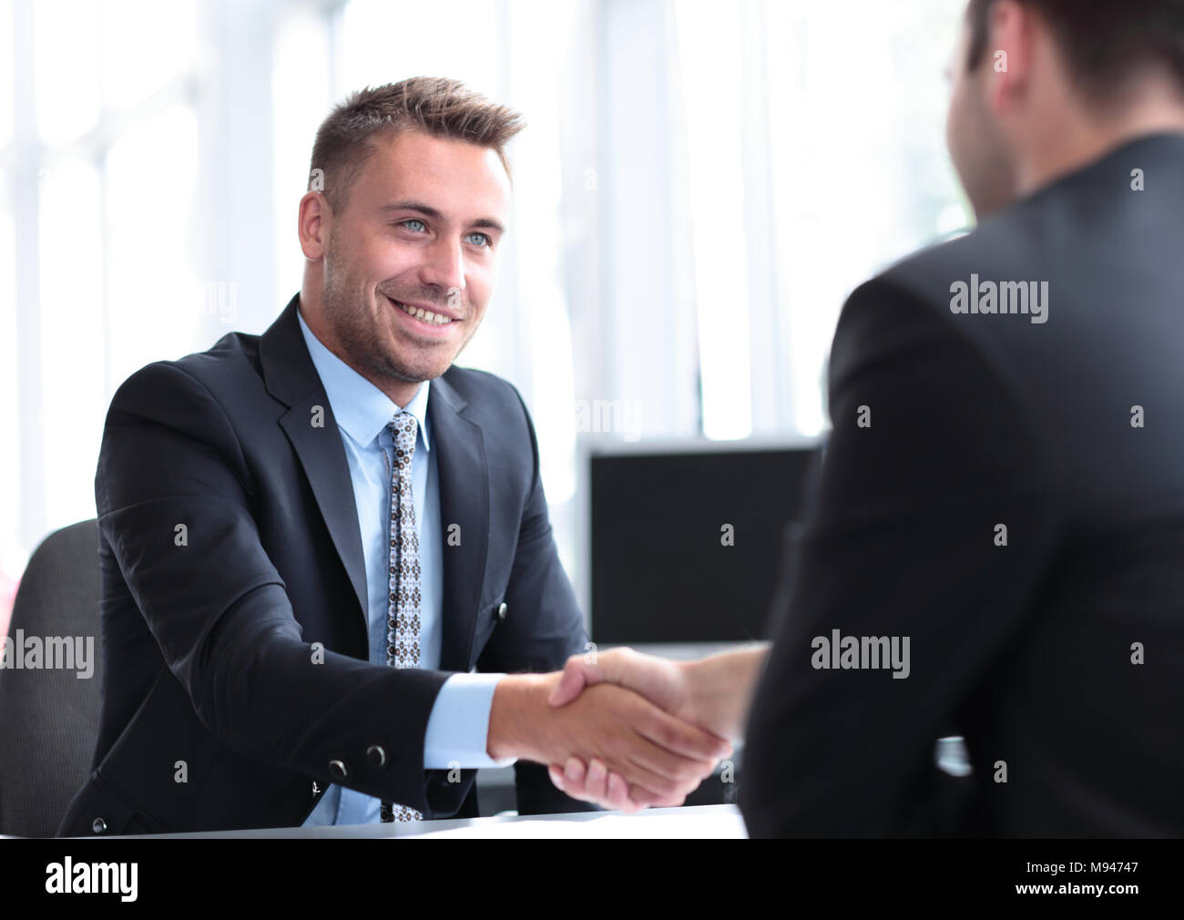 handshake of business partners sitting at a Desk Stock Photo - Alamy