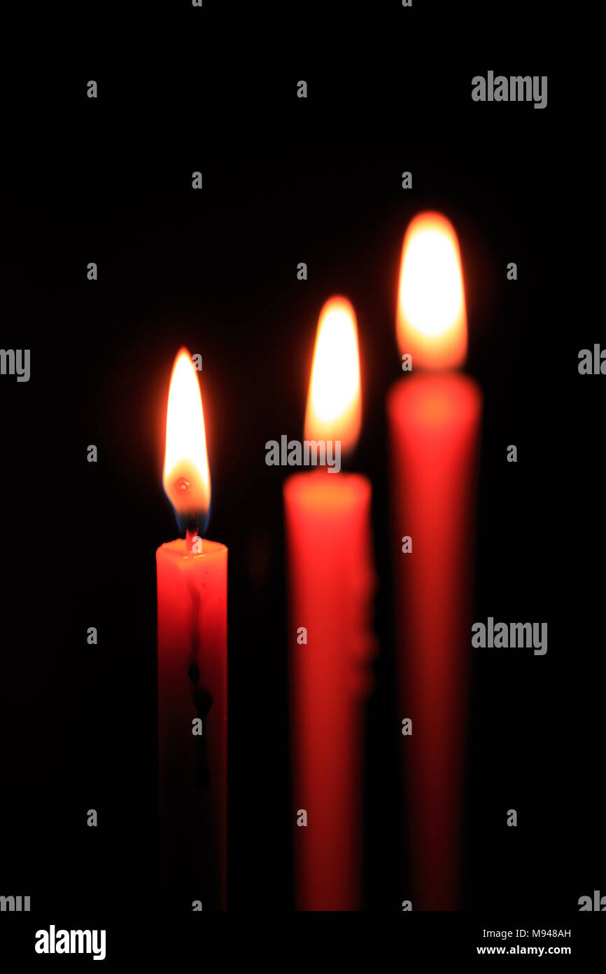 Three candles on black background Stock Photo - Alamy
