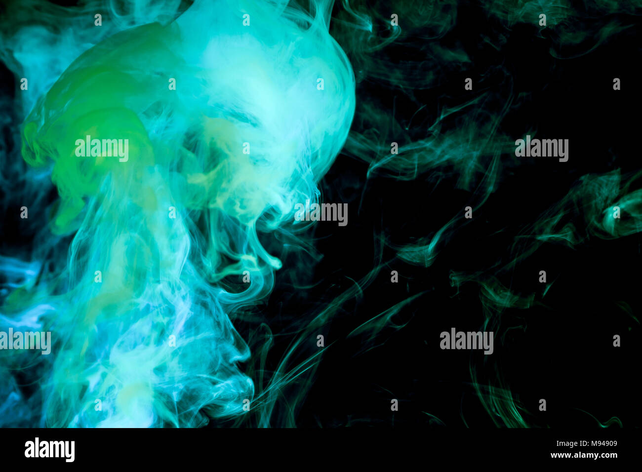 Dense multicolored smoke of blue and green colors on a black isolated ...