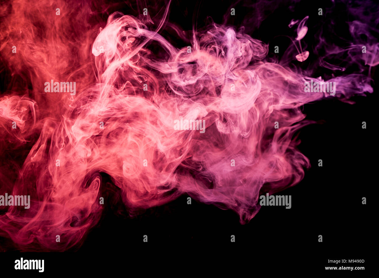 Dense multicolored smoke of pink and red colors on a black isolated ...