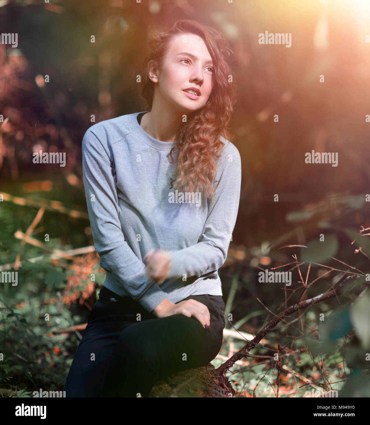 beautiful young woman sitting on a log Stock Photo - Alamy