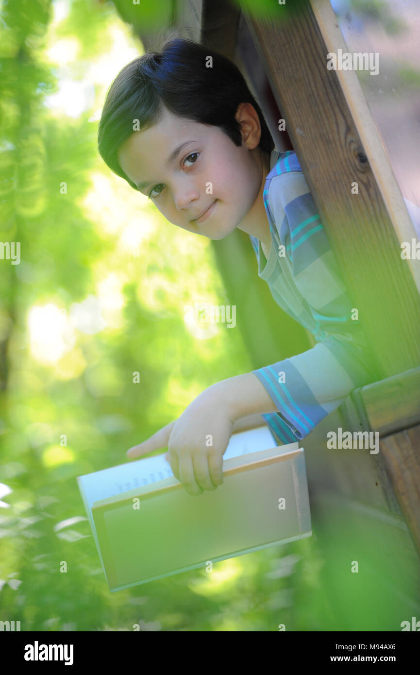 Child reading a book in the window of his hut Stock Photo - Alamy