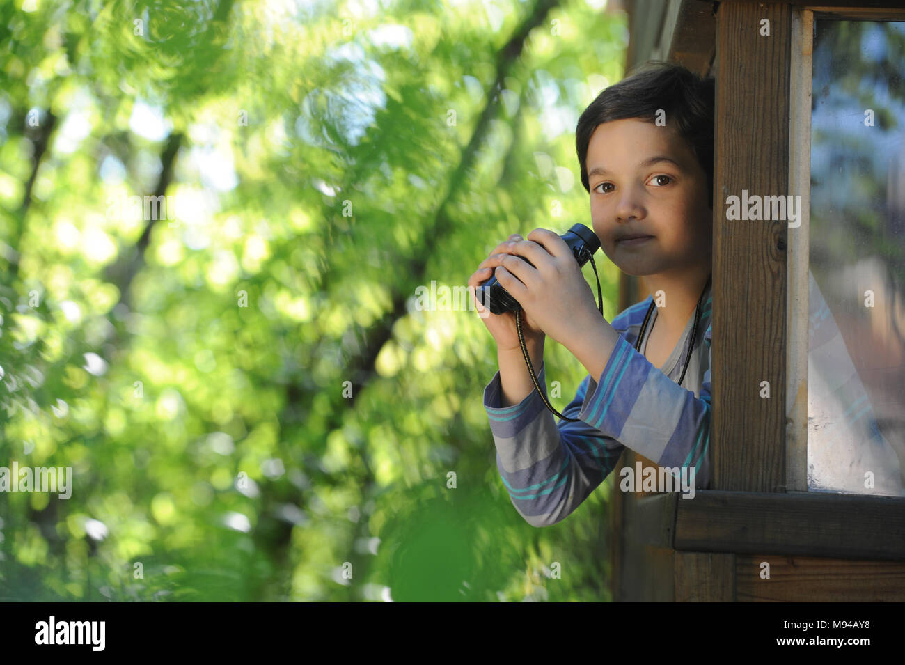 Child observing nature with a pair of binoculars at the window of his ...