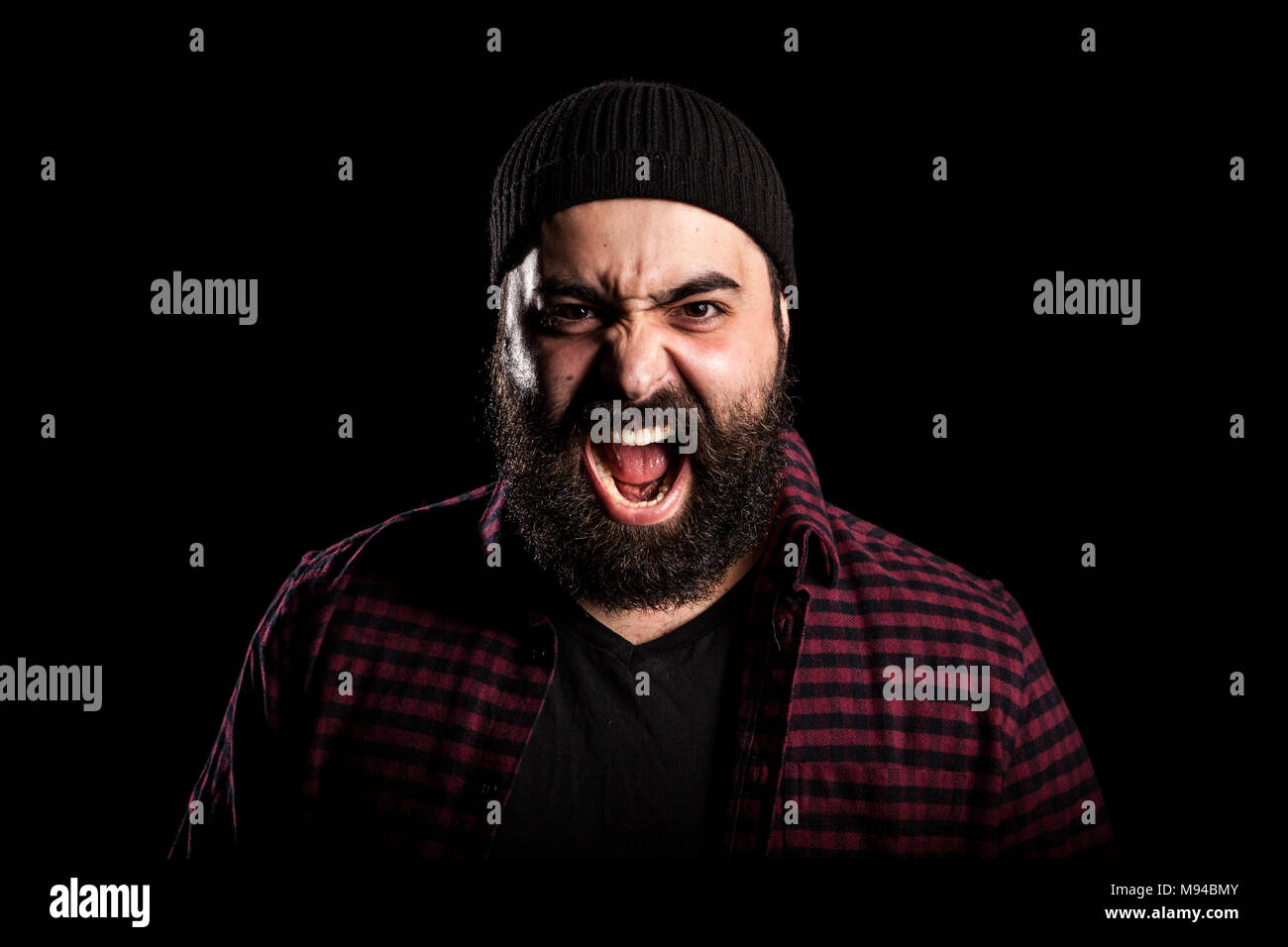 Bearded man screaming in anger on black background Stock Photo - Alamy