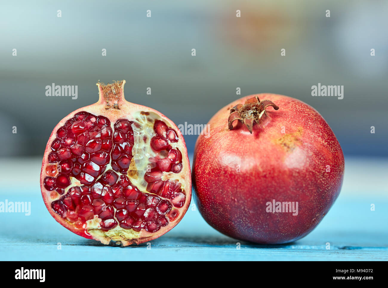 Pomegranate whole and sliced in half over blurred background Stock ...