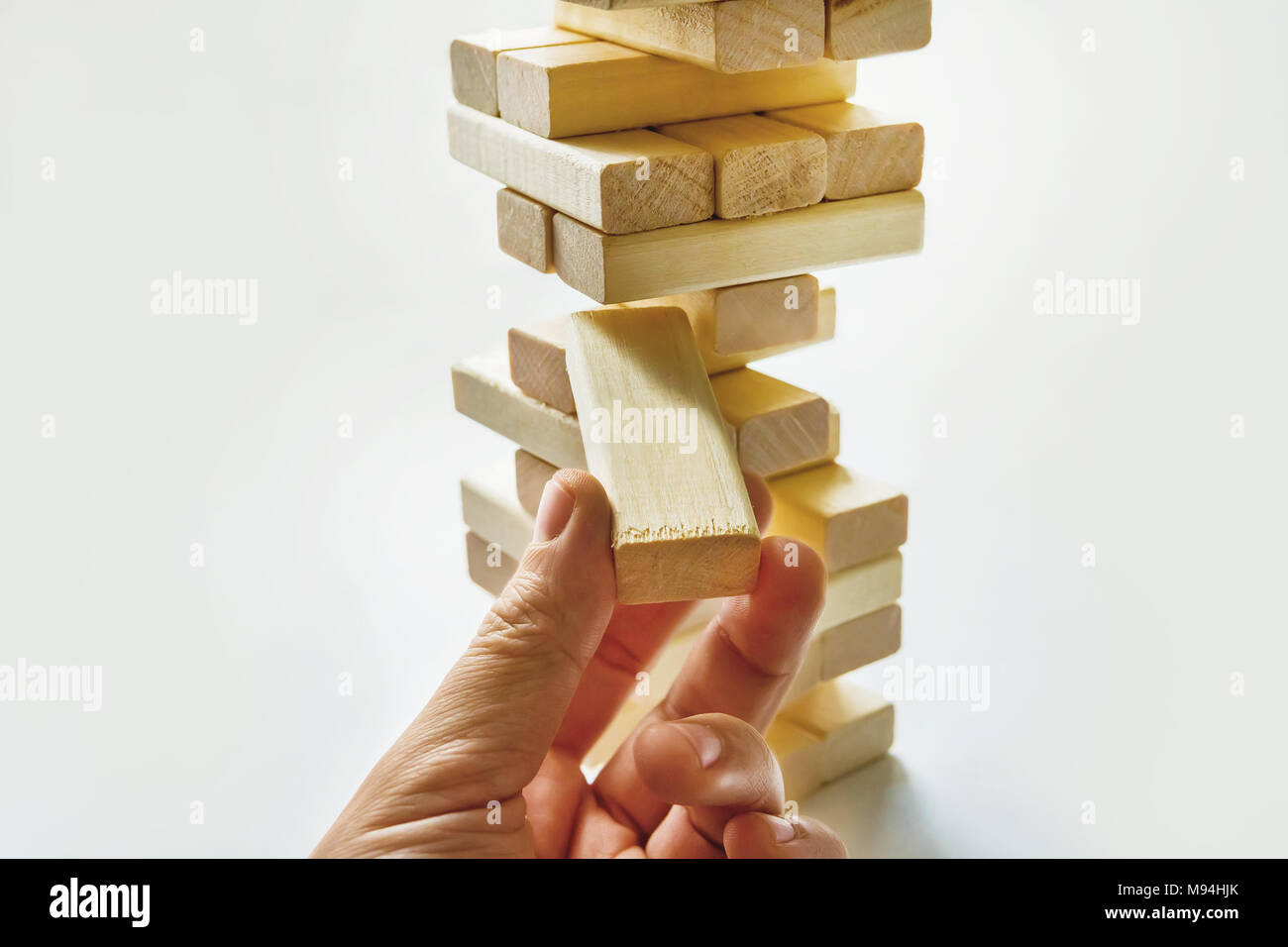 Hand playing with the wood game jenga on white background close-up ...