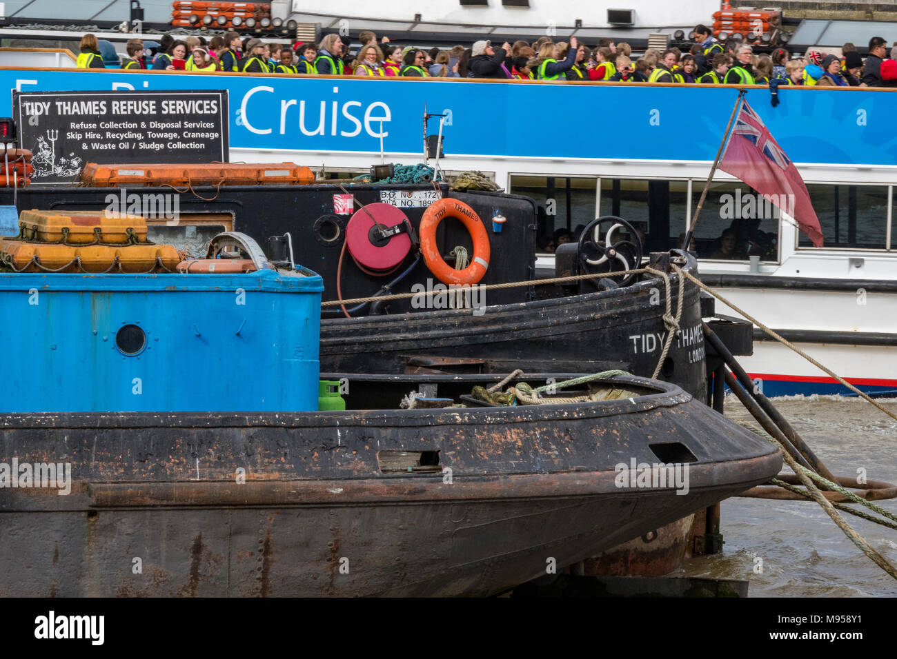 tourists on a river cruise boat passing some old working tugs and ...