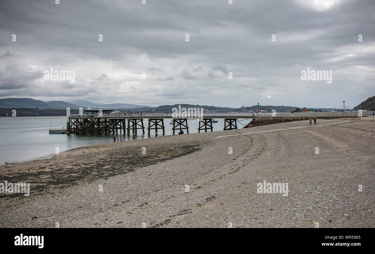 Pier in British coastal town,wide beach,people and cloudy sky.Beaumaris ...