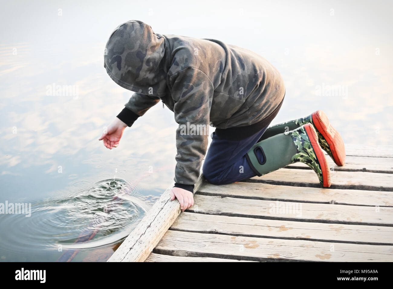 A child playing with water off a dock Stock Photo - Alamy