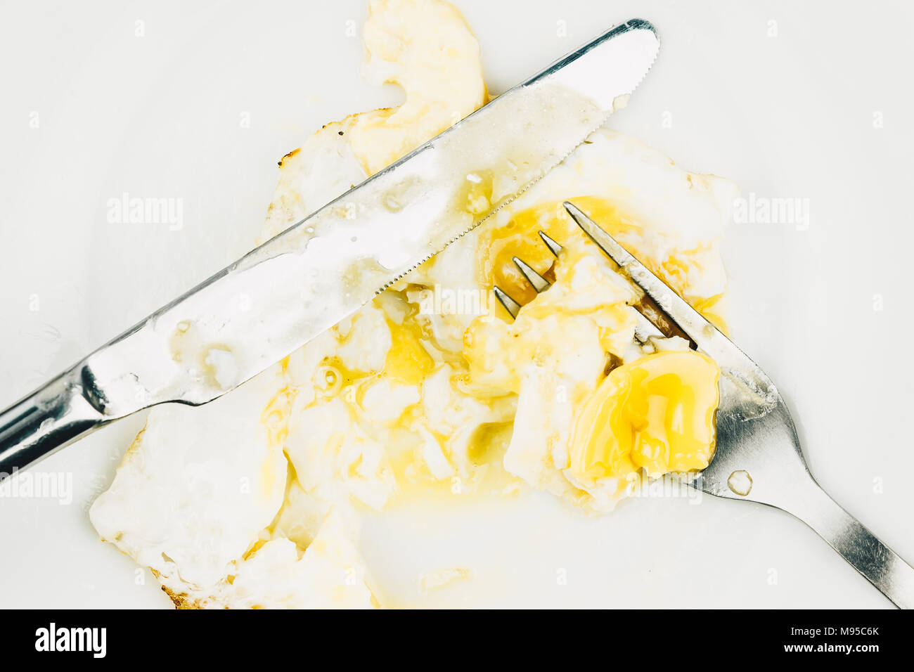 The remnants of food in plate. Fork and knife in a white plate with ...